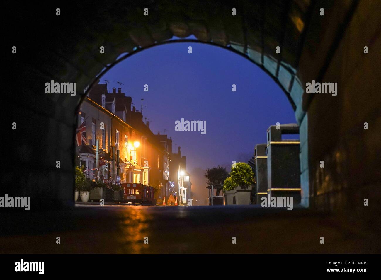 Cobbled tunnel opening out to a street-lit, night time street scene ...