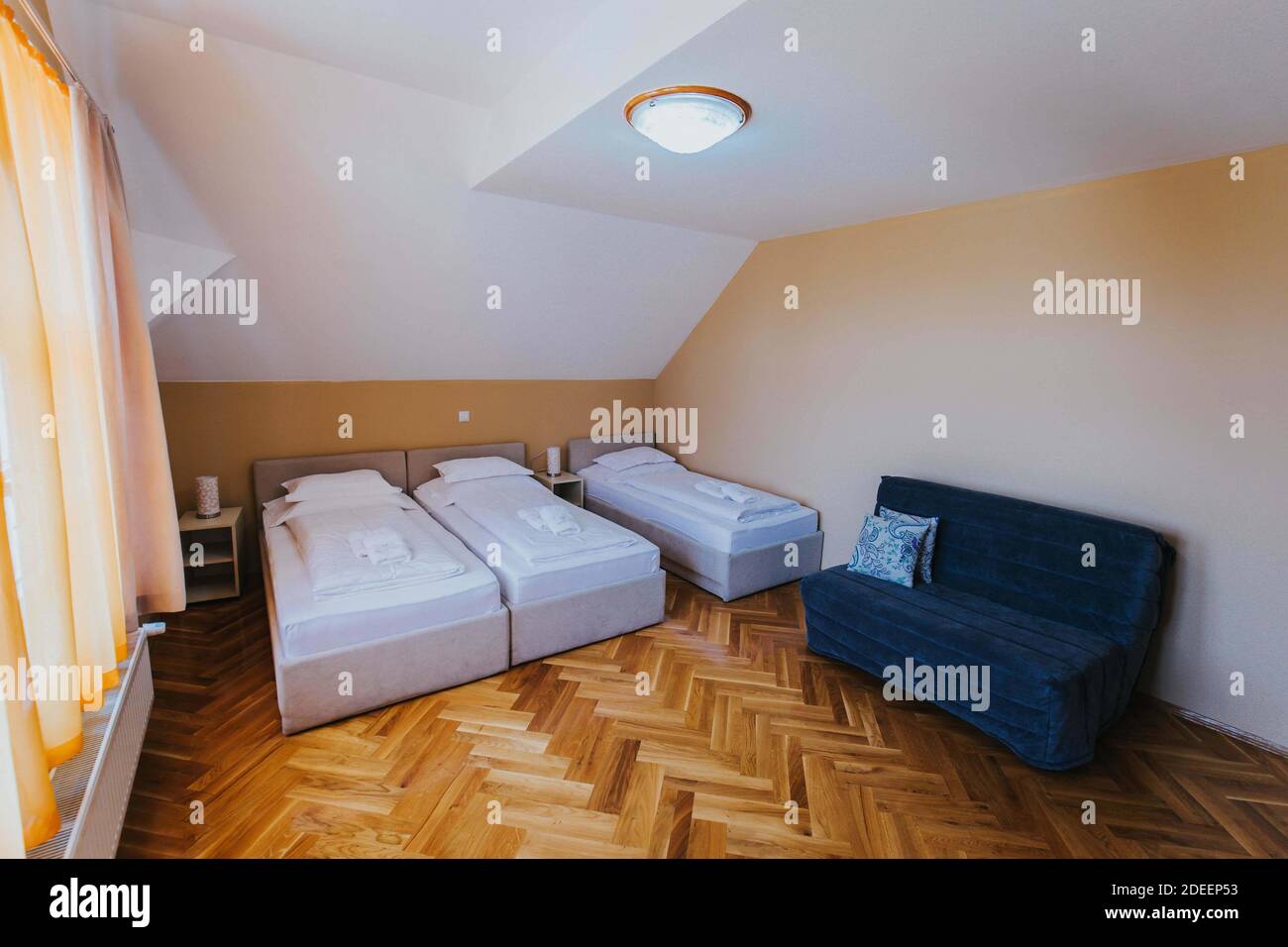 A hotel room for three people with three beds and a couch Stock Photo ...