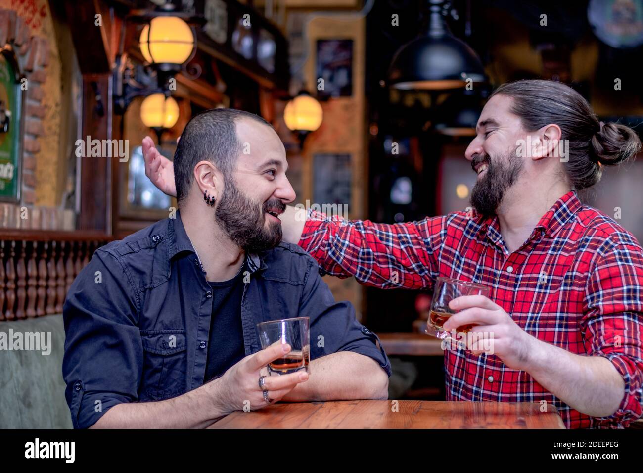 Two male friends drinking whiskey together at the pub. One of them is ...