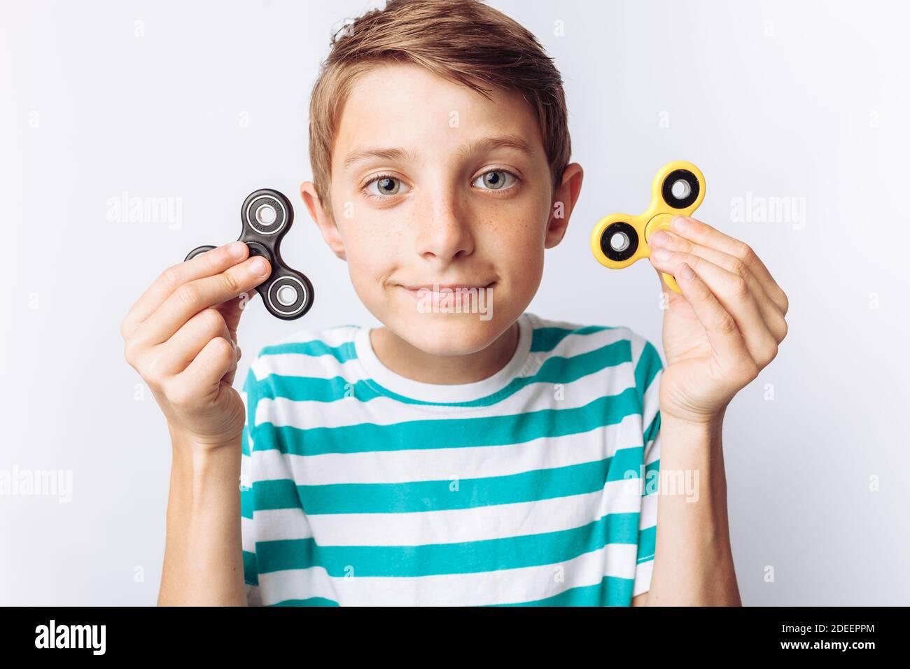 Portrait of a beautiful and emotional boy, holding spinners, plays ...