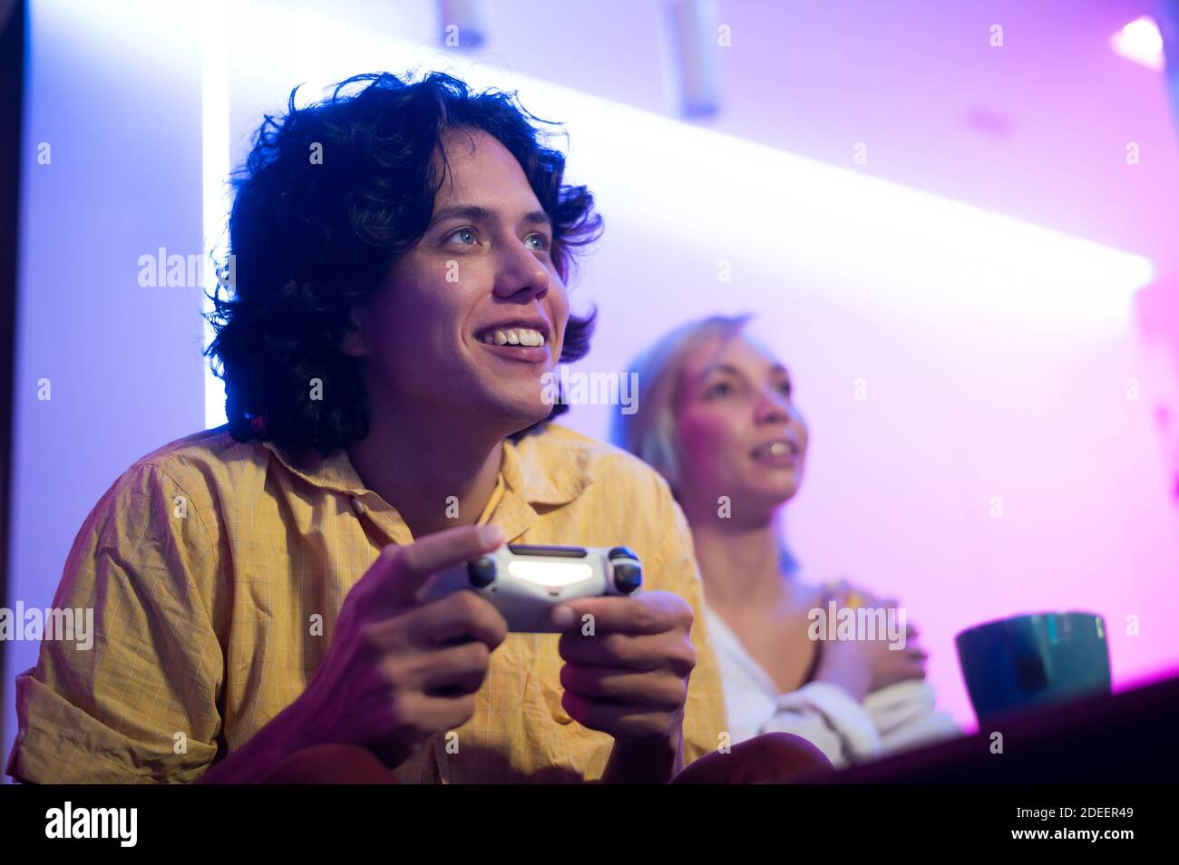 Young curly man and his girlfriend playing gaming console using ...