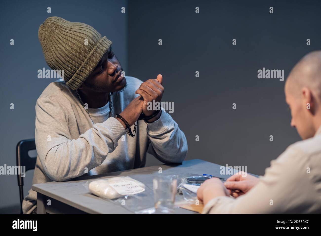 Black accused guy in police station for questioning with a bag of white ...