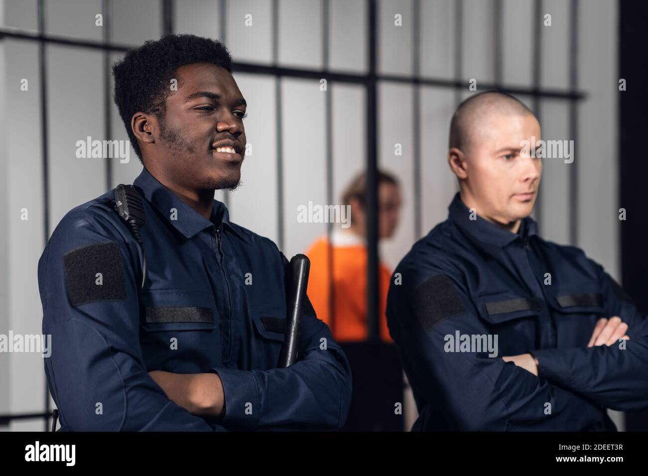Black and white prison guards stand with batons in the background of ...