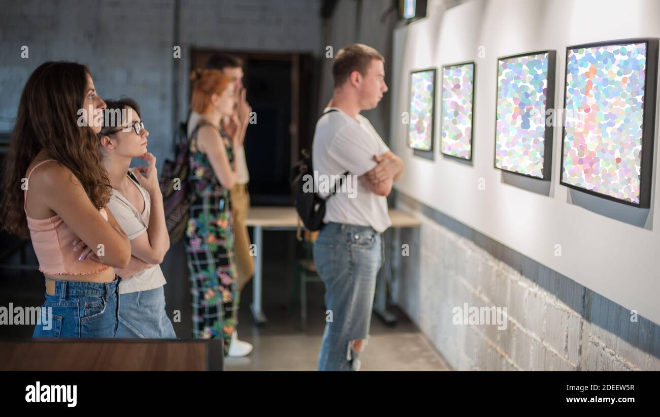 Group of friends in modern art exhibition gallery hall contemplating ...