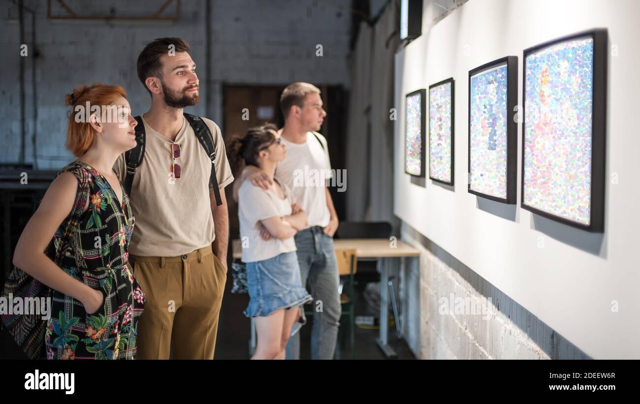 Group of friends in modern art exhibition gallery hall contemplating ...