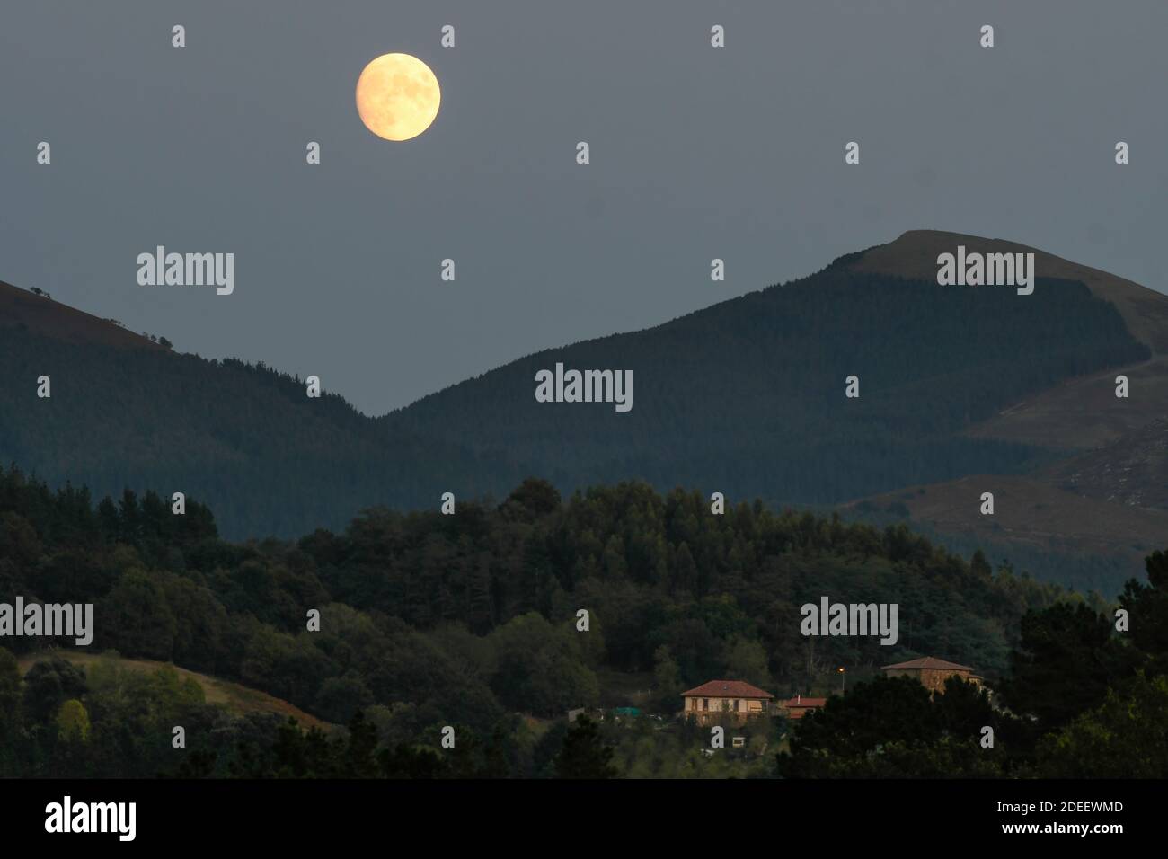 The Moon rising between the mountains at dusk Stock Photo - Alamy