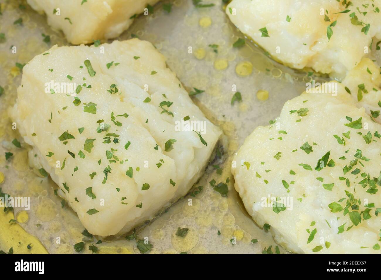 Close-up of some hake loins in green sauce with parsley and oil ...