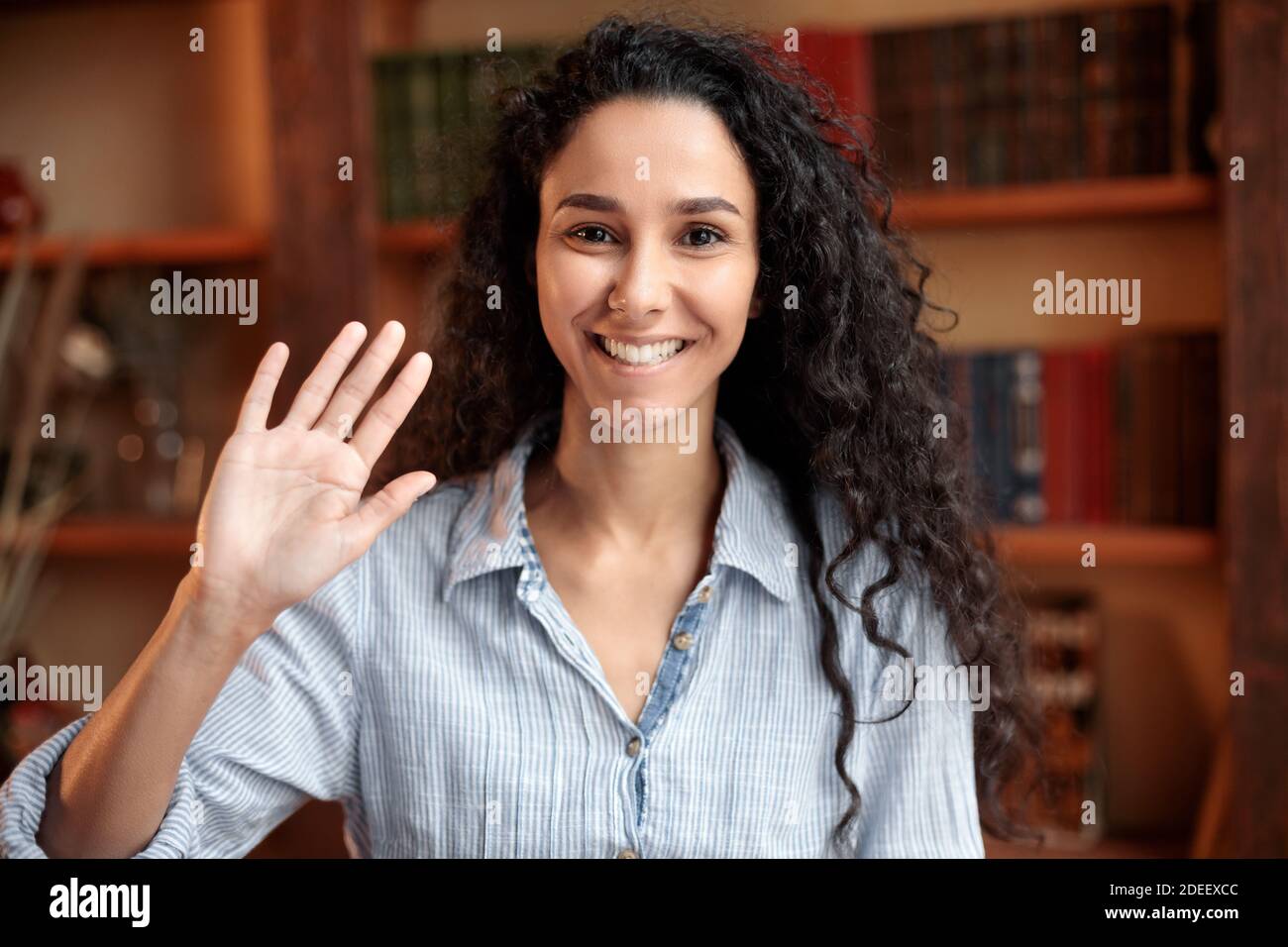 Woman waving to camera having online call Stock Photo - Alamy