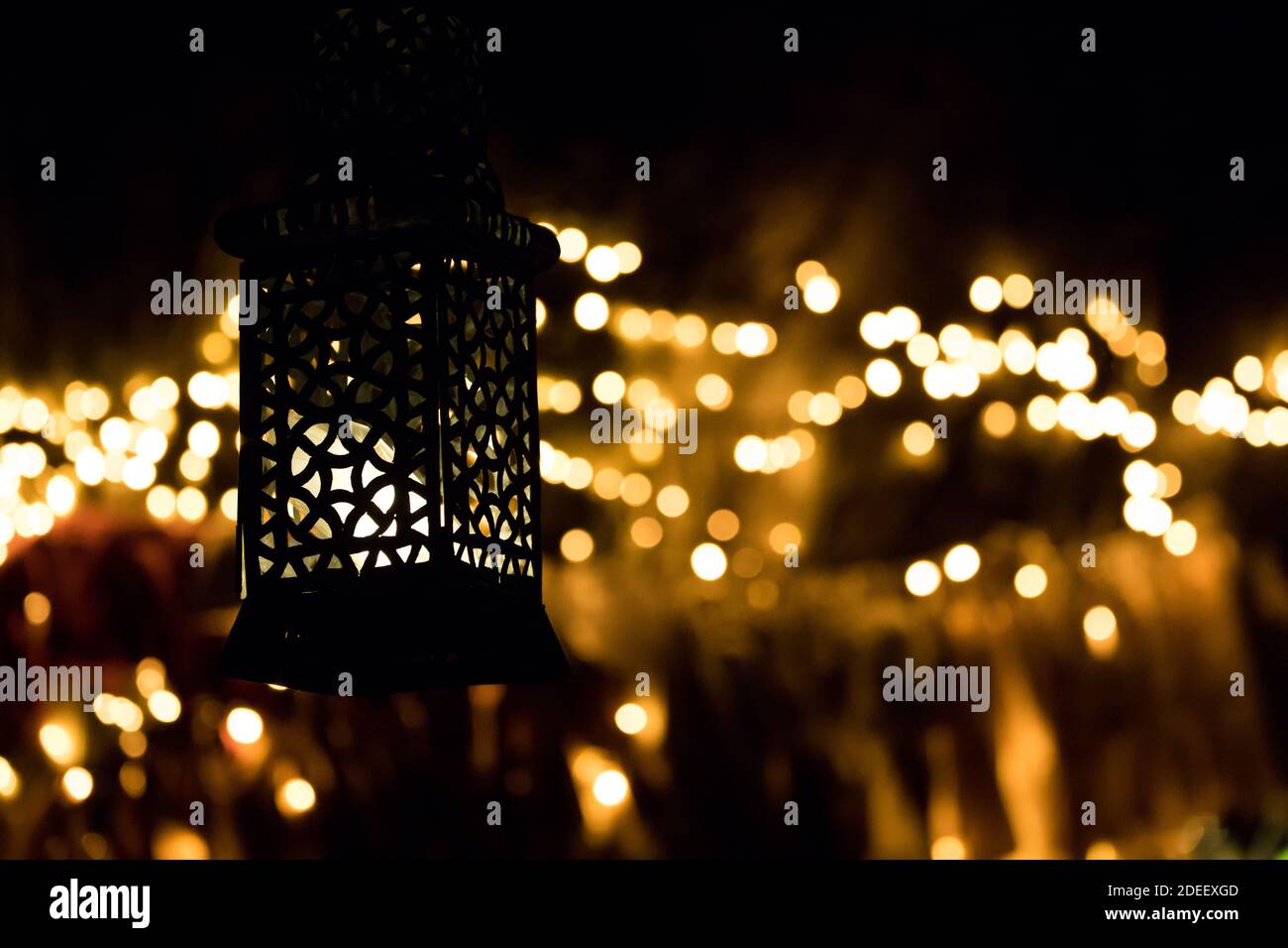 Closeup of a burning lantern hanging in the sky with bright lights in ...