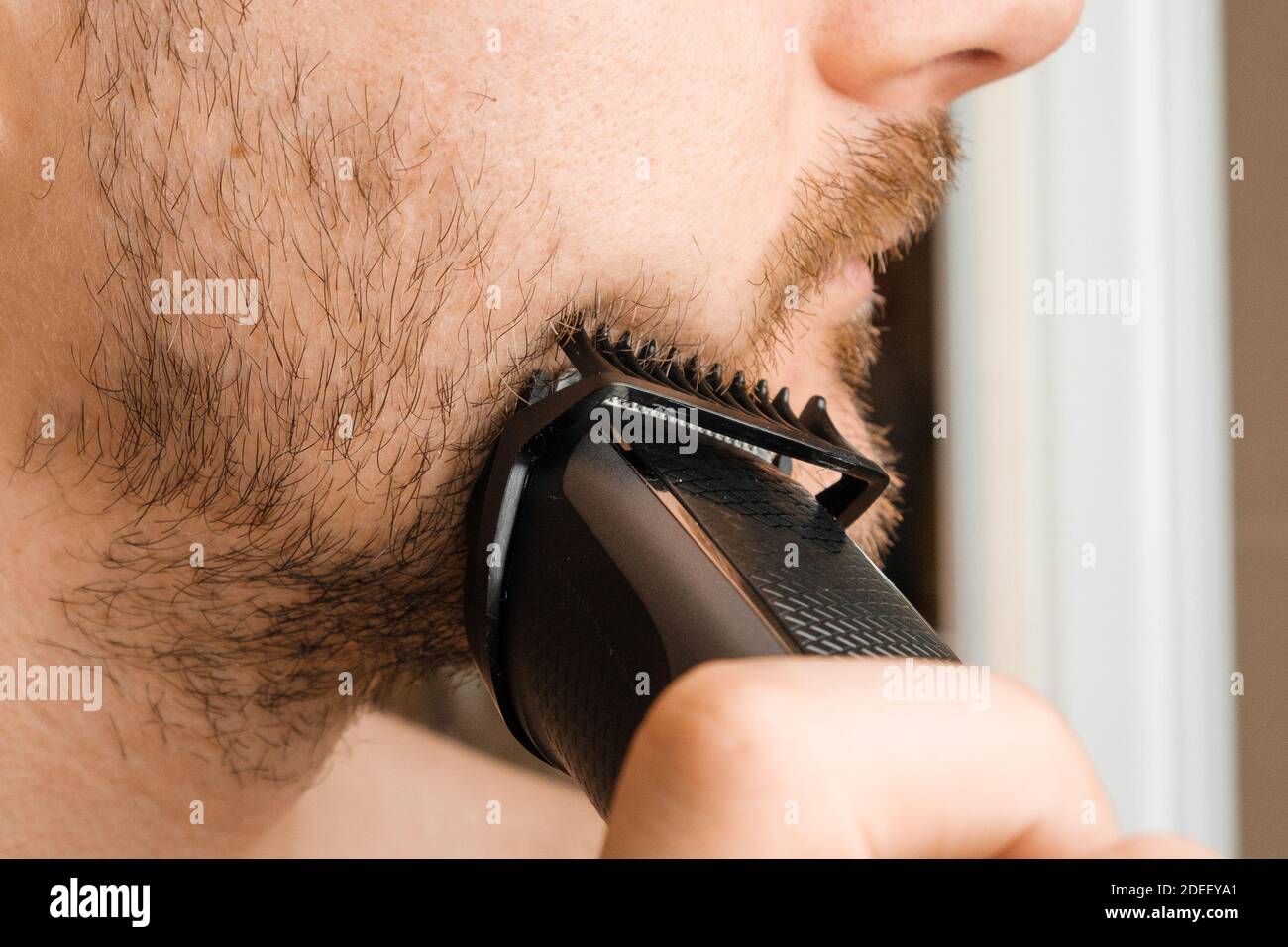Man shaving beard and cheeks with an electric razor. Morning routine ...