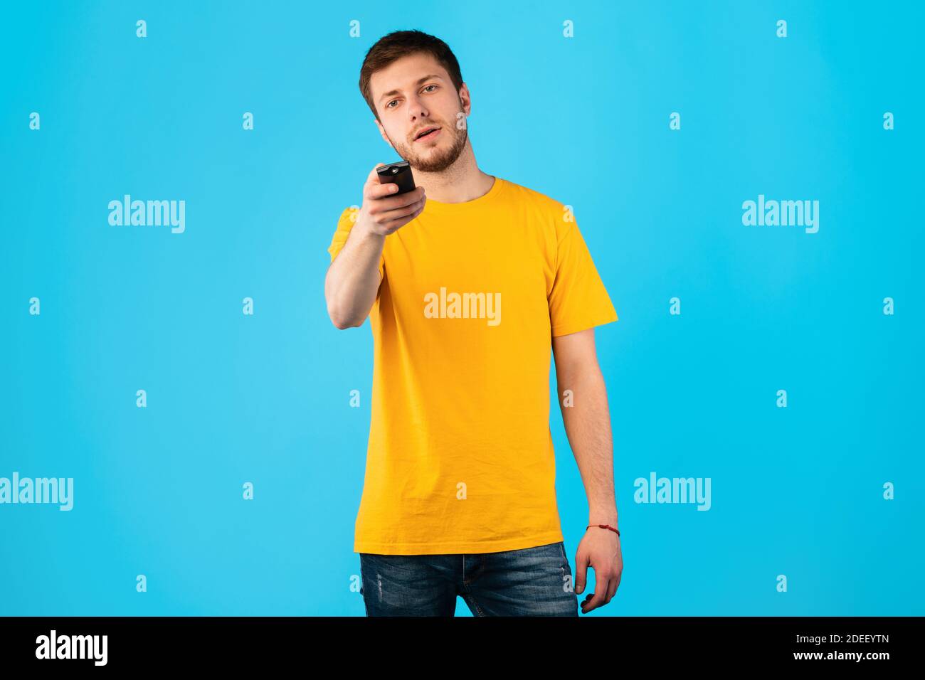 Guy holding remote control isolated on blue background Stock Photo - Alamy