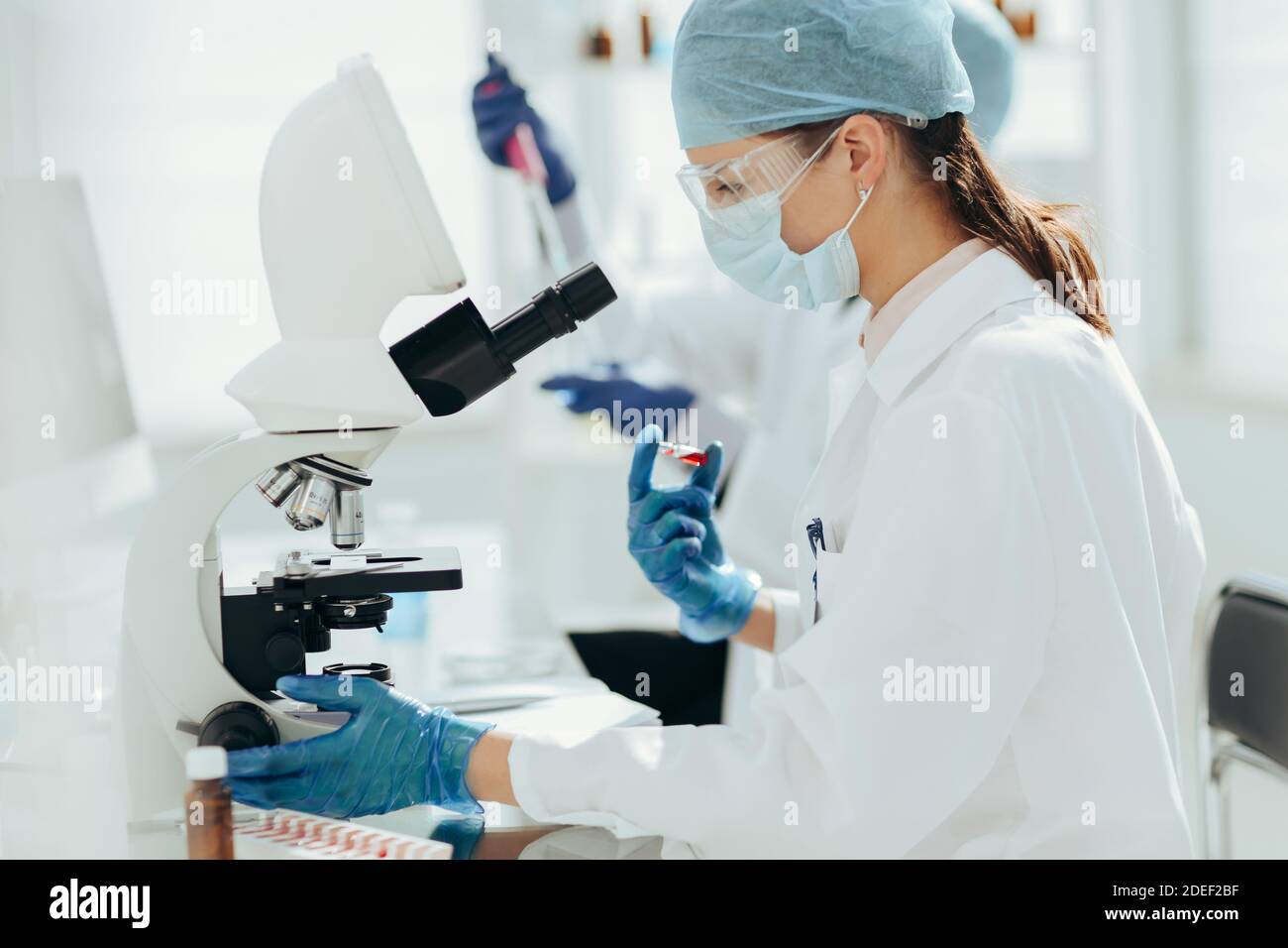 female scientist sitting in front of a microscope Stock Photo - Alamy
