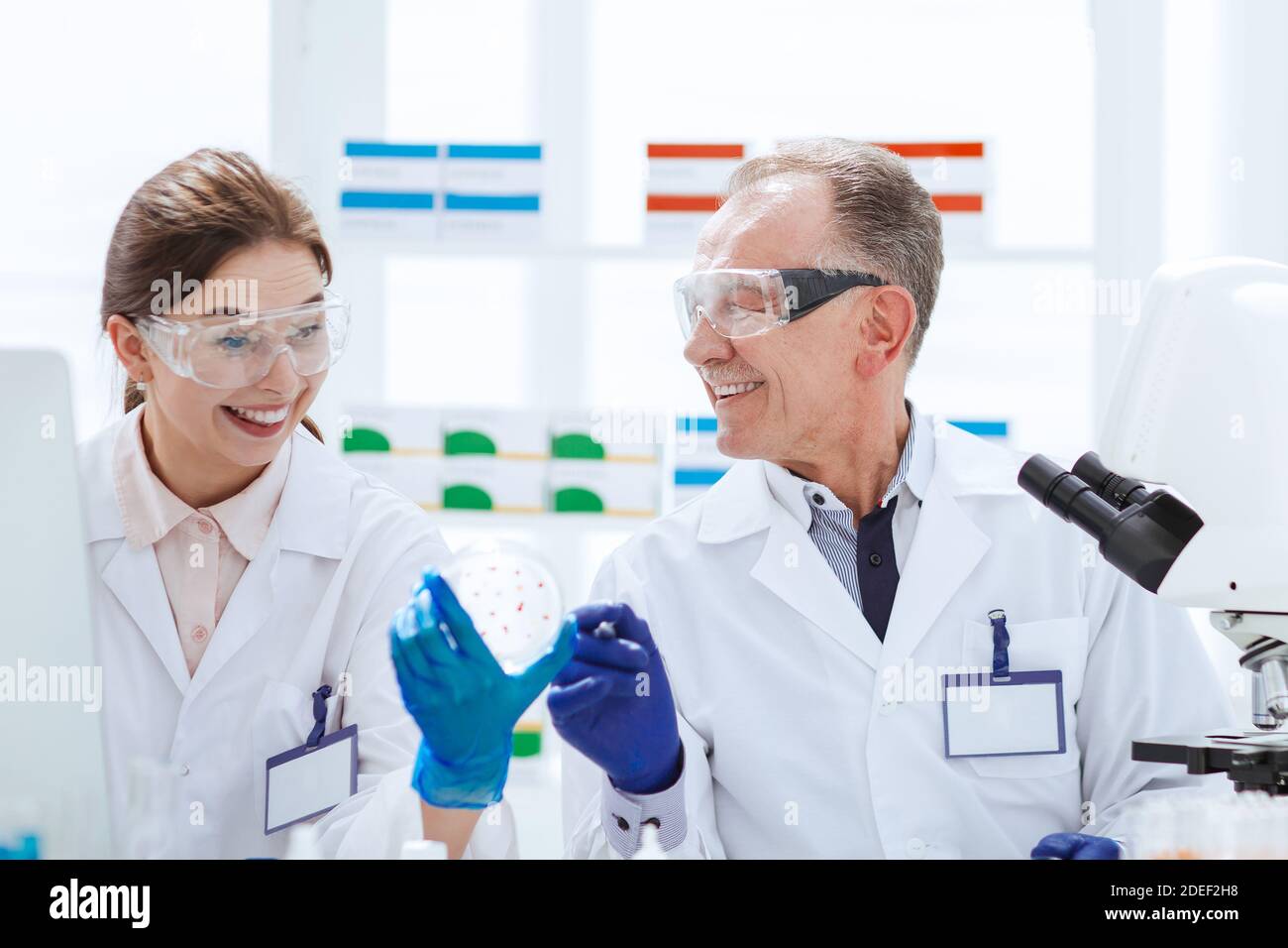 smiling scientists with a Petri dish sitting at a laboratory table ...