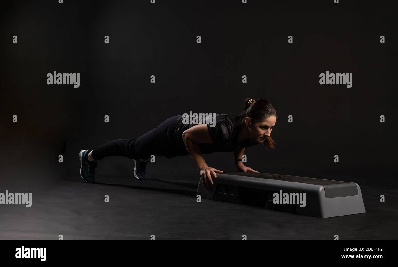 Fitness on step platforms, does exercises pressed. Engaged in sports on ...