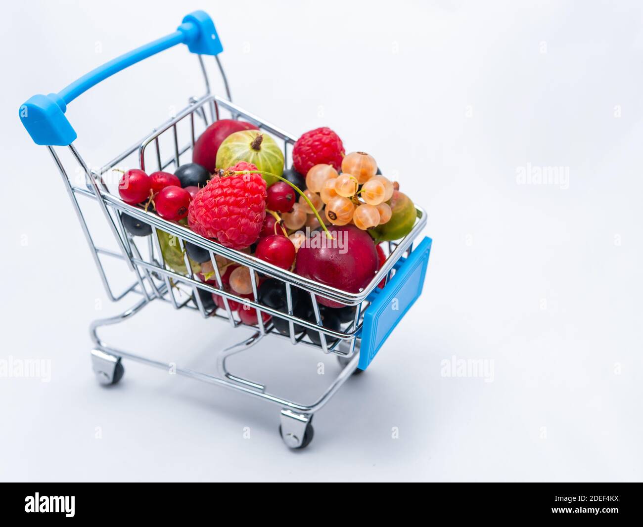 Mini grocery cart filled with fresh vitamin berries isolated on white ...