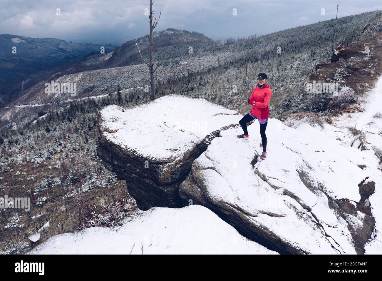 Aerial view of a smiling female runner in a red sweatshirt standing on ...