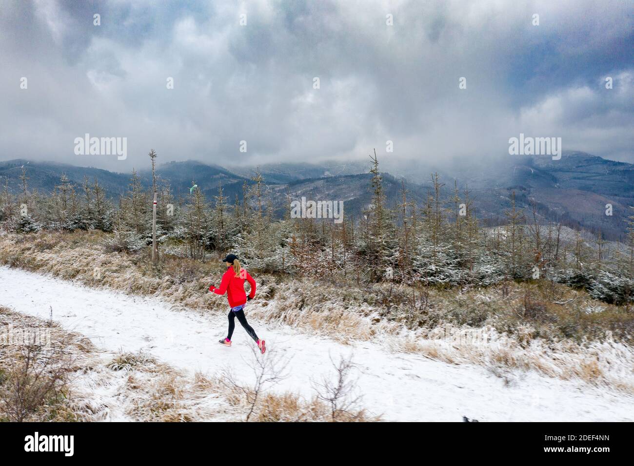 Drone view of a female runner on a trail in the winter mountains in the ...