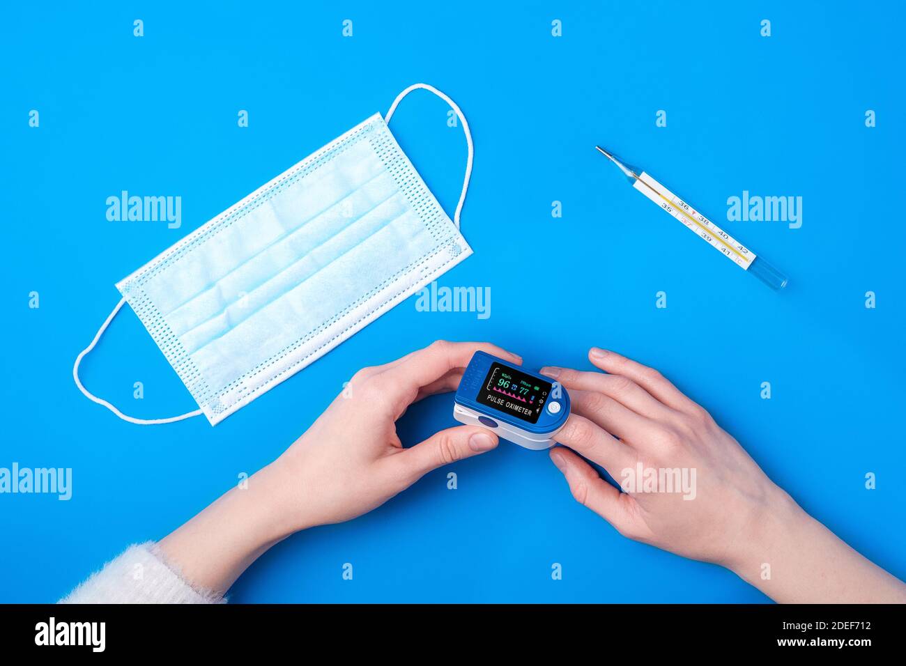 Person using pulse oximeter device on finger near to thermometer and ...