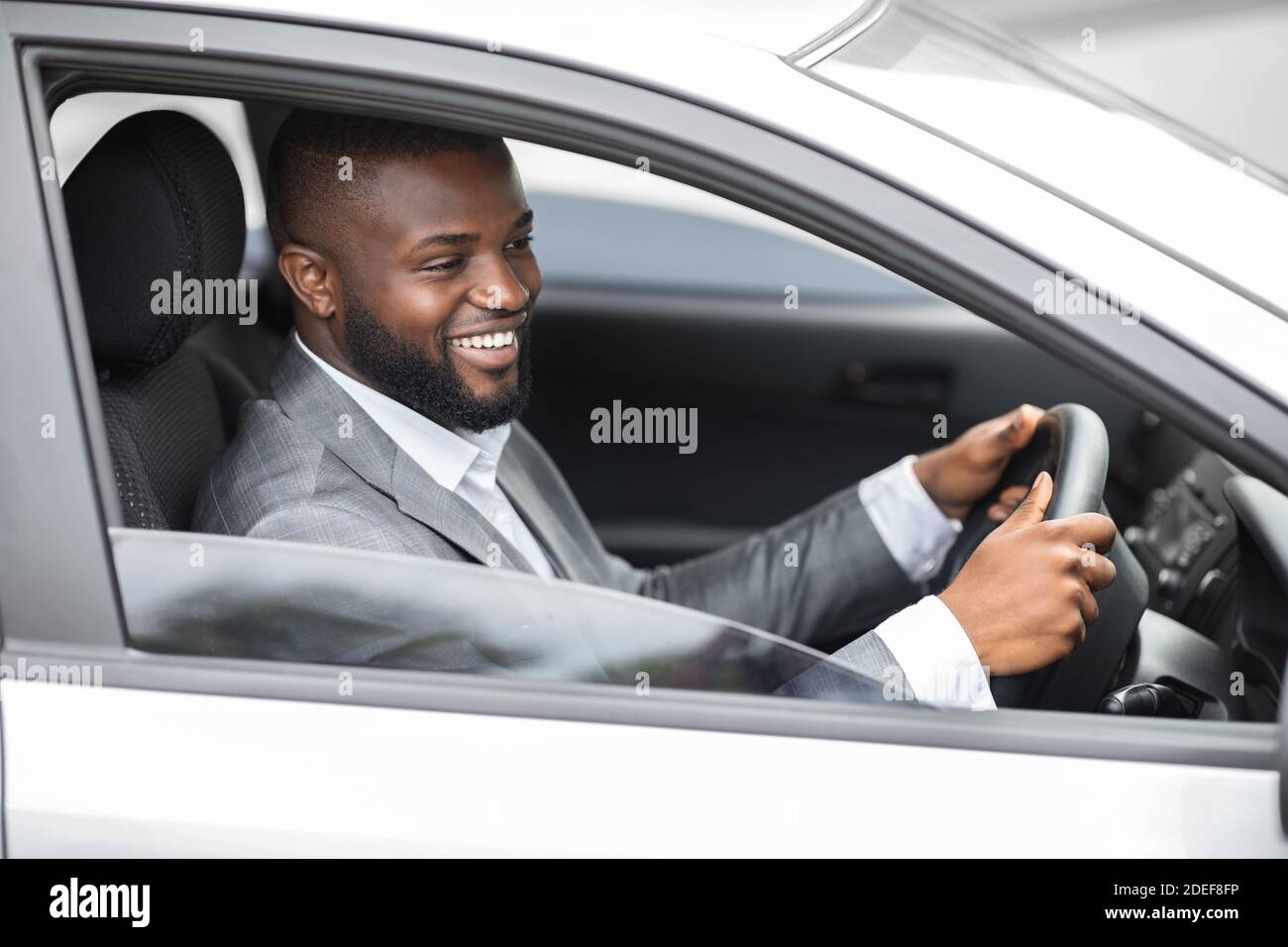 Happy black businessman driving home after working day Stock Photo - Alamy