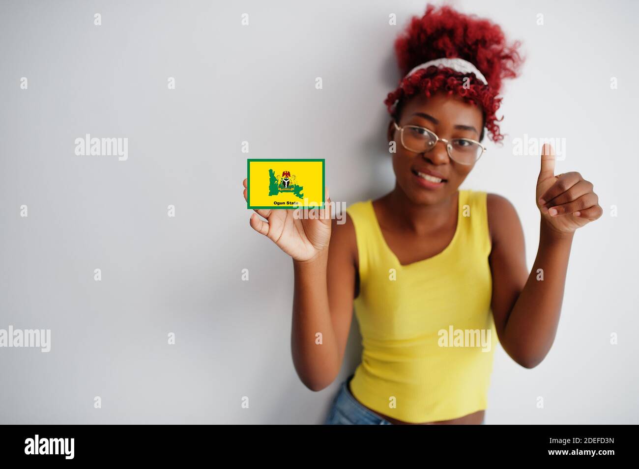 African woman with afro hair hold Ogun flag isolated on white ...