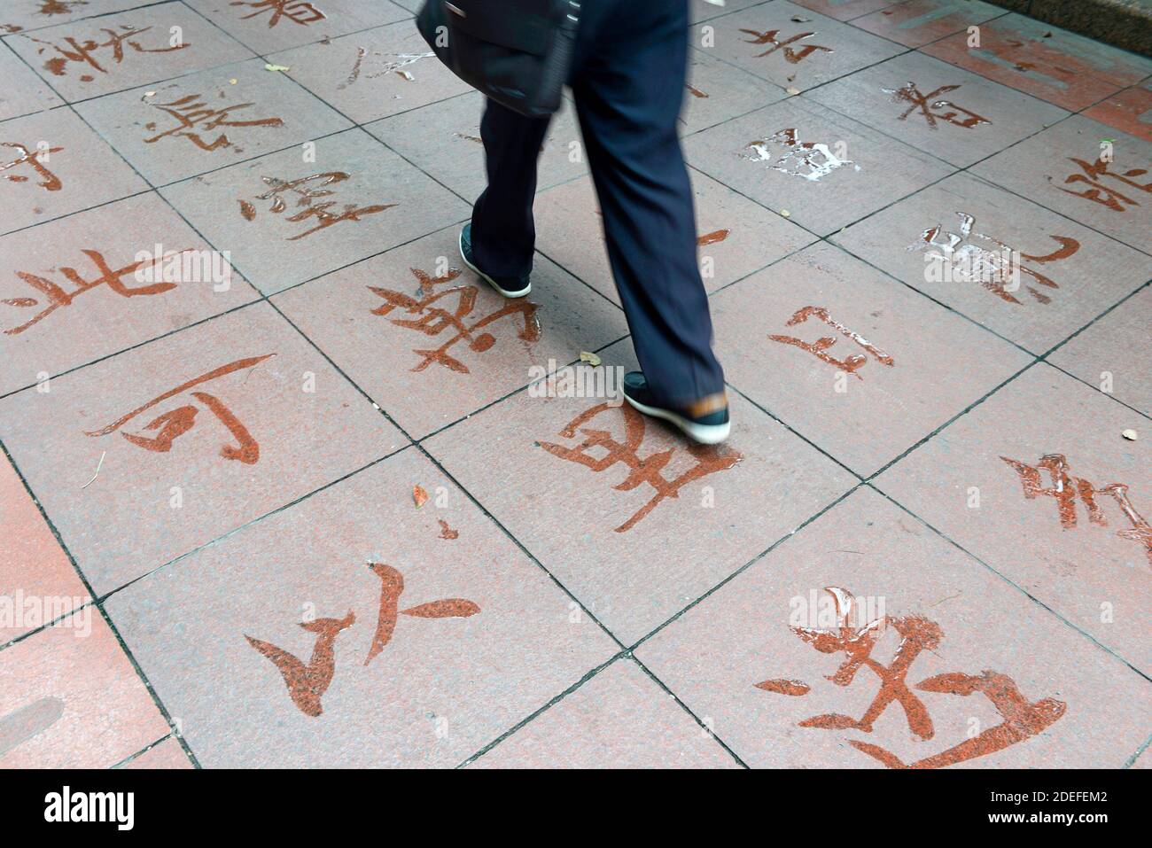A person walks over water calligraphy on the pavement in Guiyang, China ...