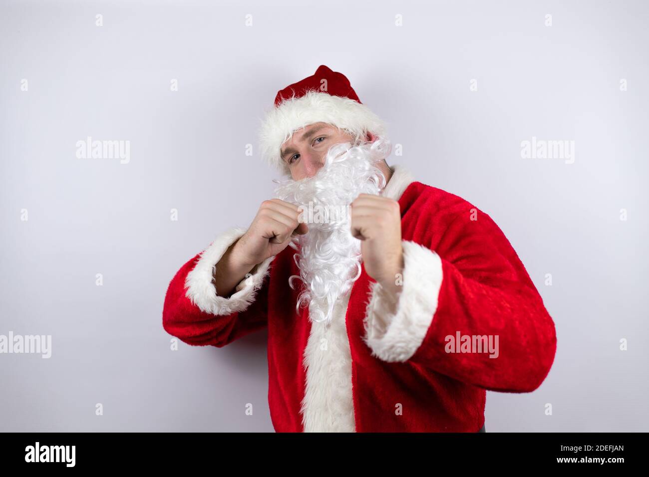 Man dressed as Santa Claus standing over isolated white background ...