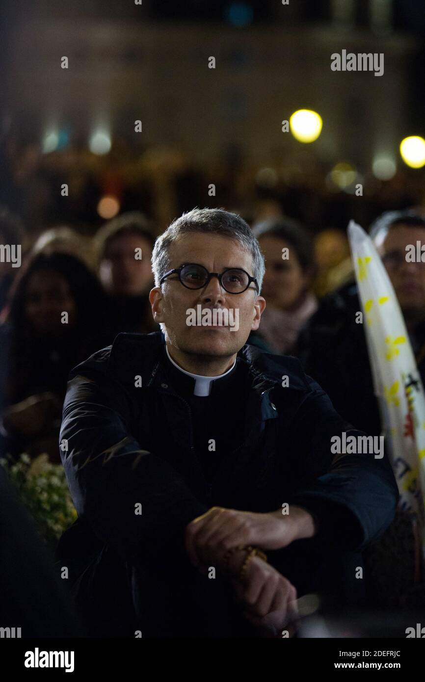 A priest praying with candles on the place saint michel in front of a ...