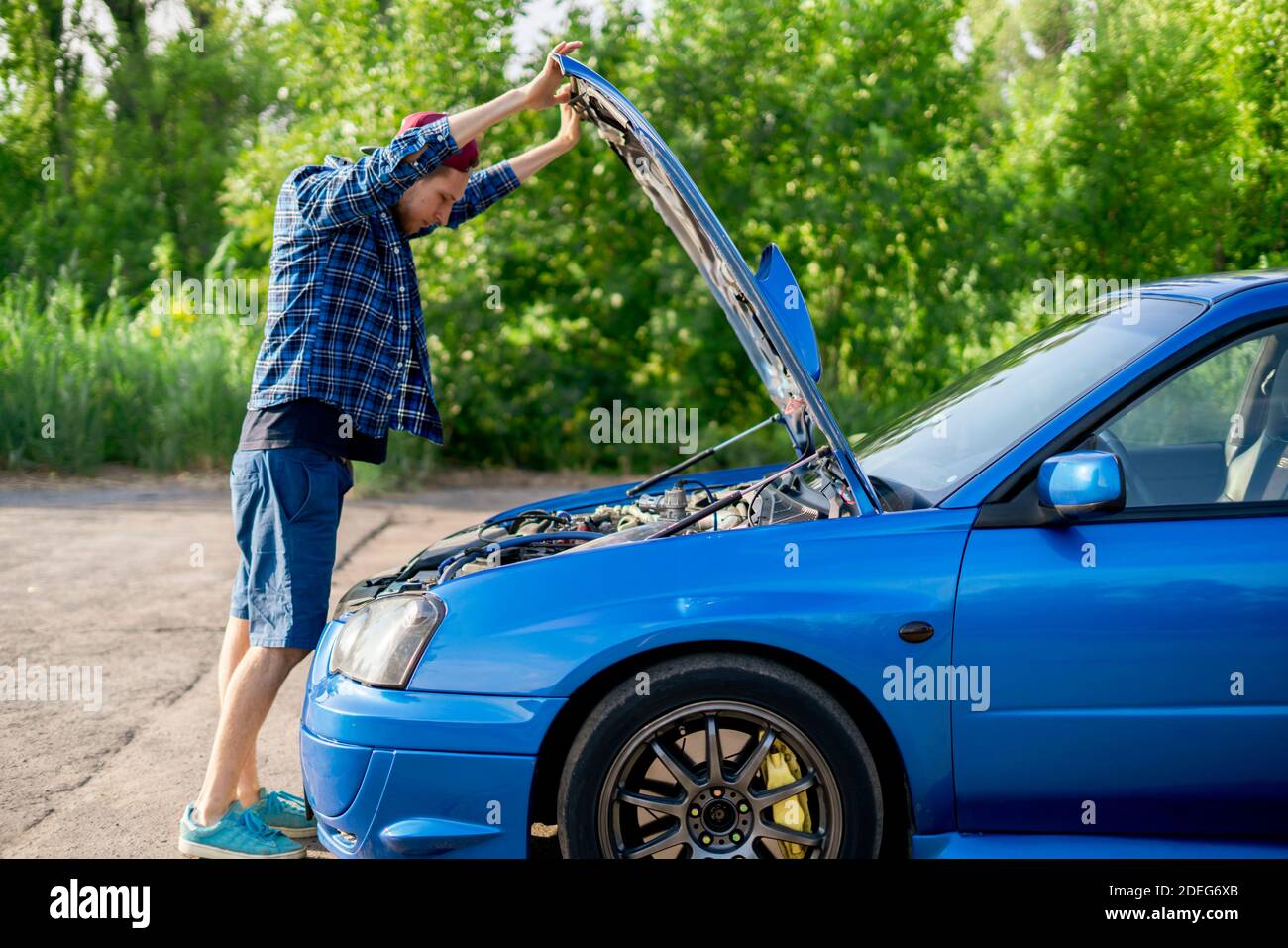 the sad disappointed man standing near the car with opened hood, fix ...