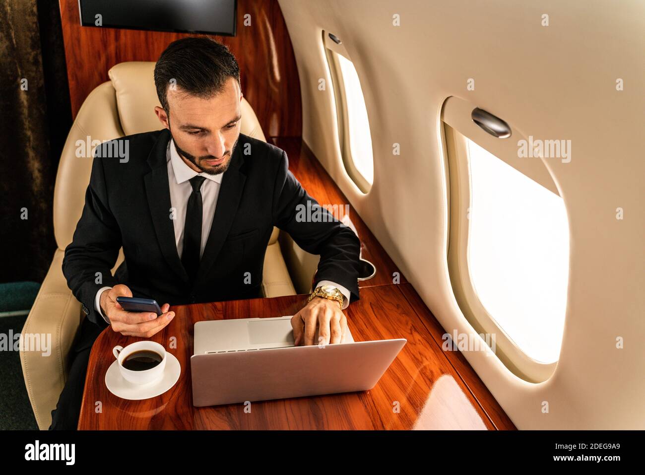 Handsome businessman wearing elegant suit flying on exclusive private ...