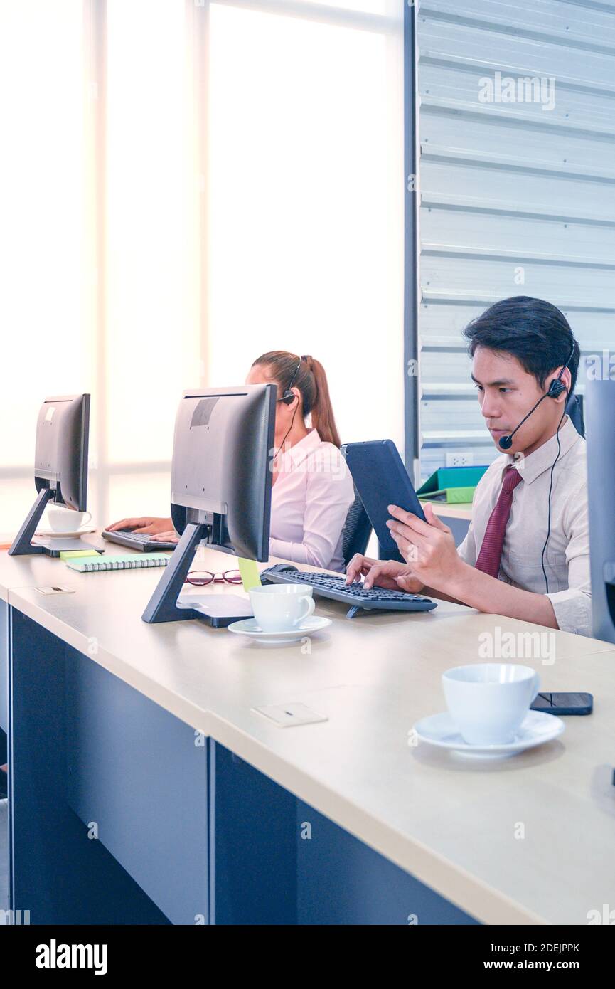 Young customer service men agent with headsets and computer working at ...