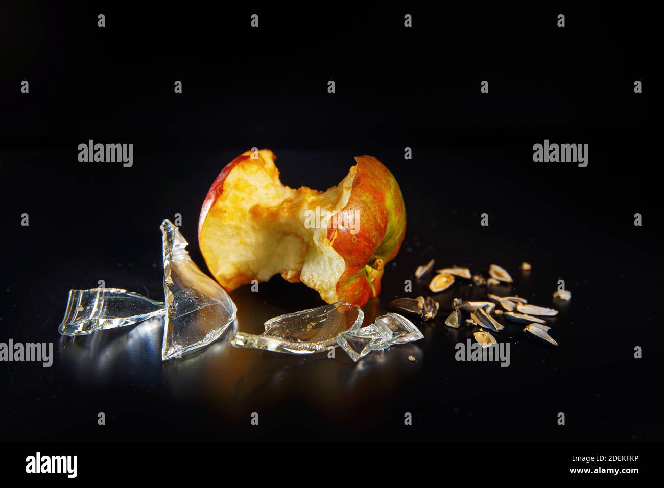 Apple core, glass shards and other debris on a black background with ...