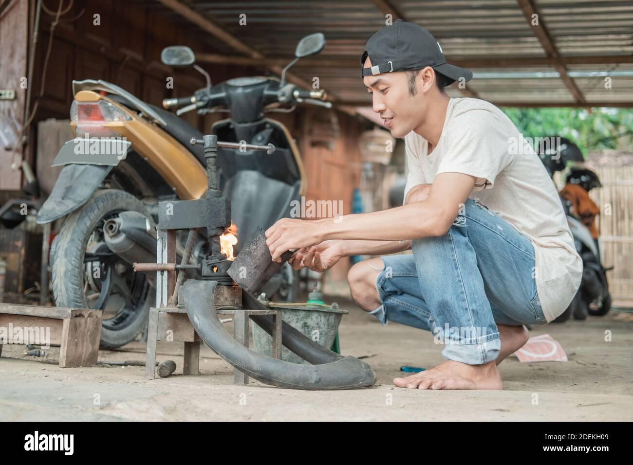 Tire repairman lights a fire with a lighter on a traditional press ...