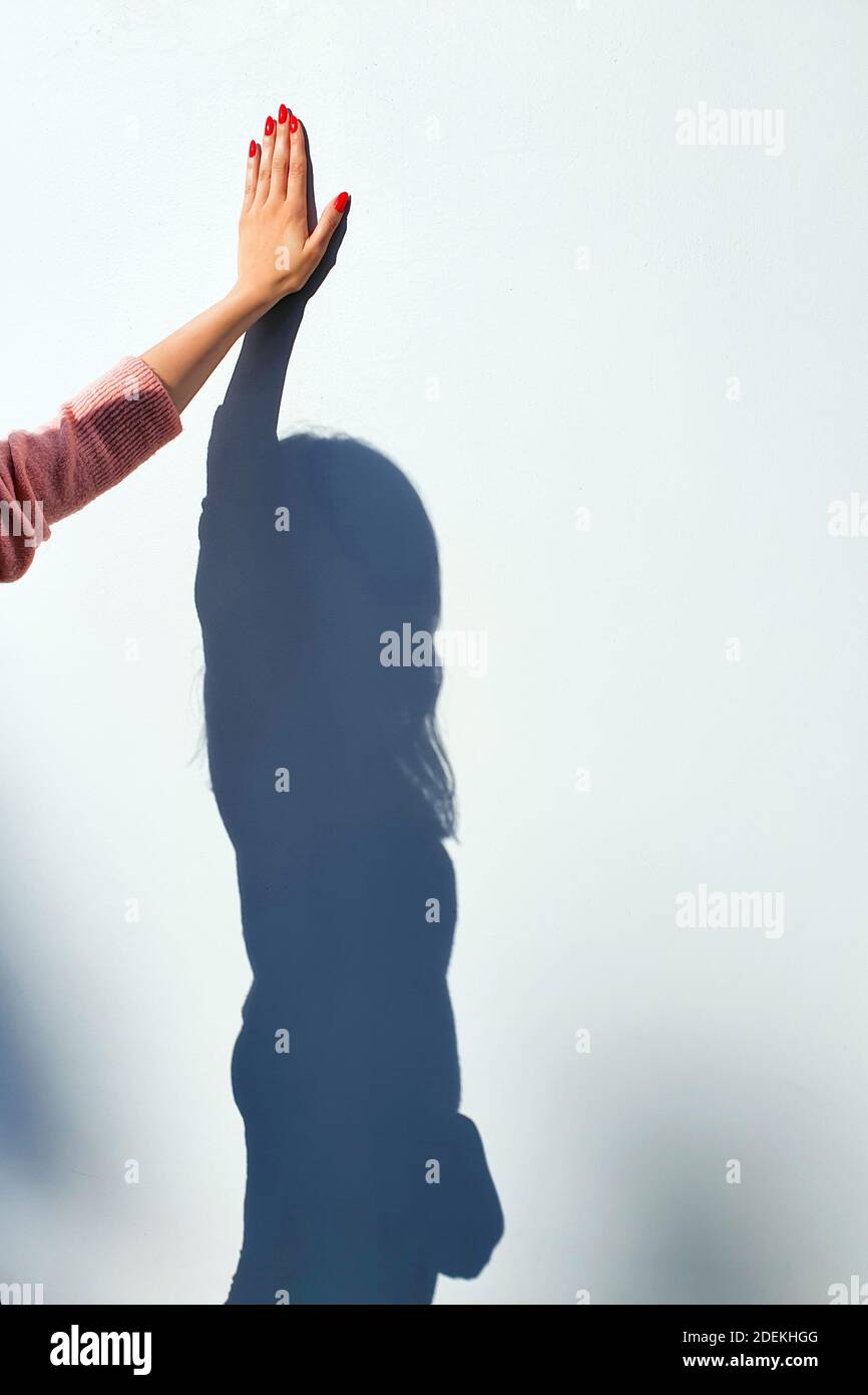 Female hand with red nails and shadow on gray wall, high five sign ...