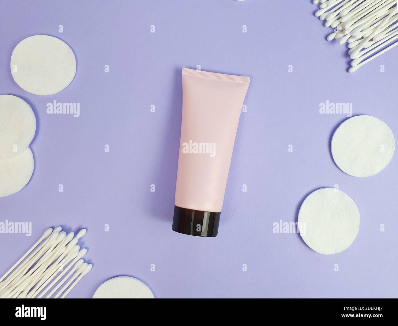 Light pink squeeze bottle cosmetic tube with black cap, cotton pads and ...