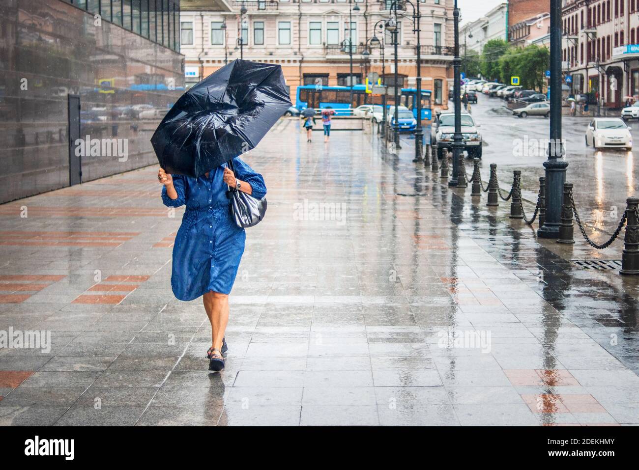 Woman in bad rainy weather walks down the street and tries to keep the ...