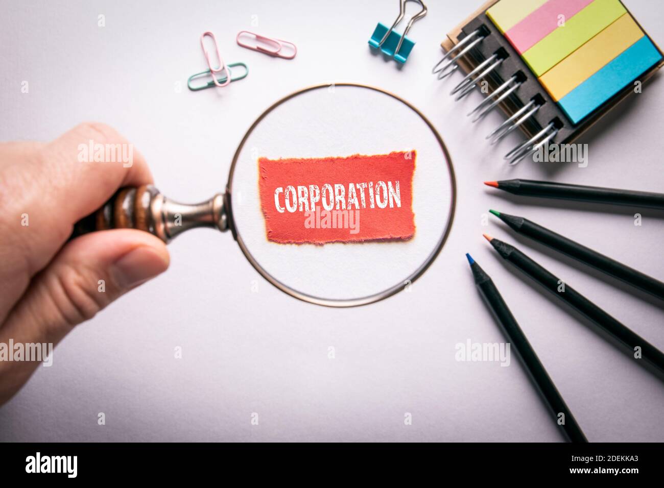 CORPORATION. Magnifying glass in a man's hand. White office desk Stock ...