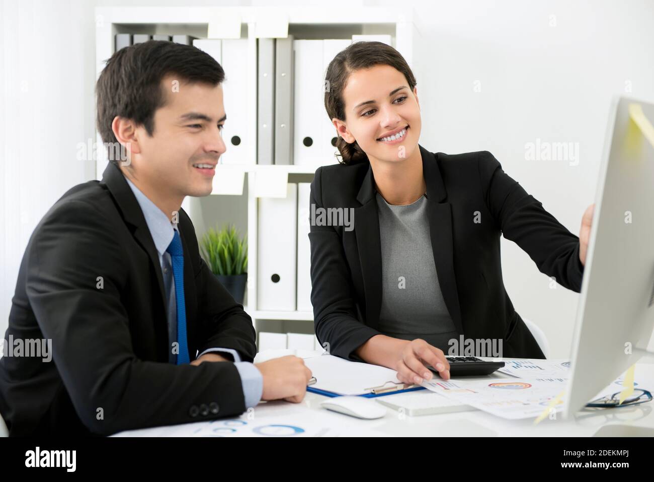 Businesswoman happily traning new male staff memeber with desktop ...