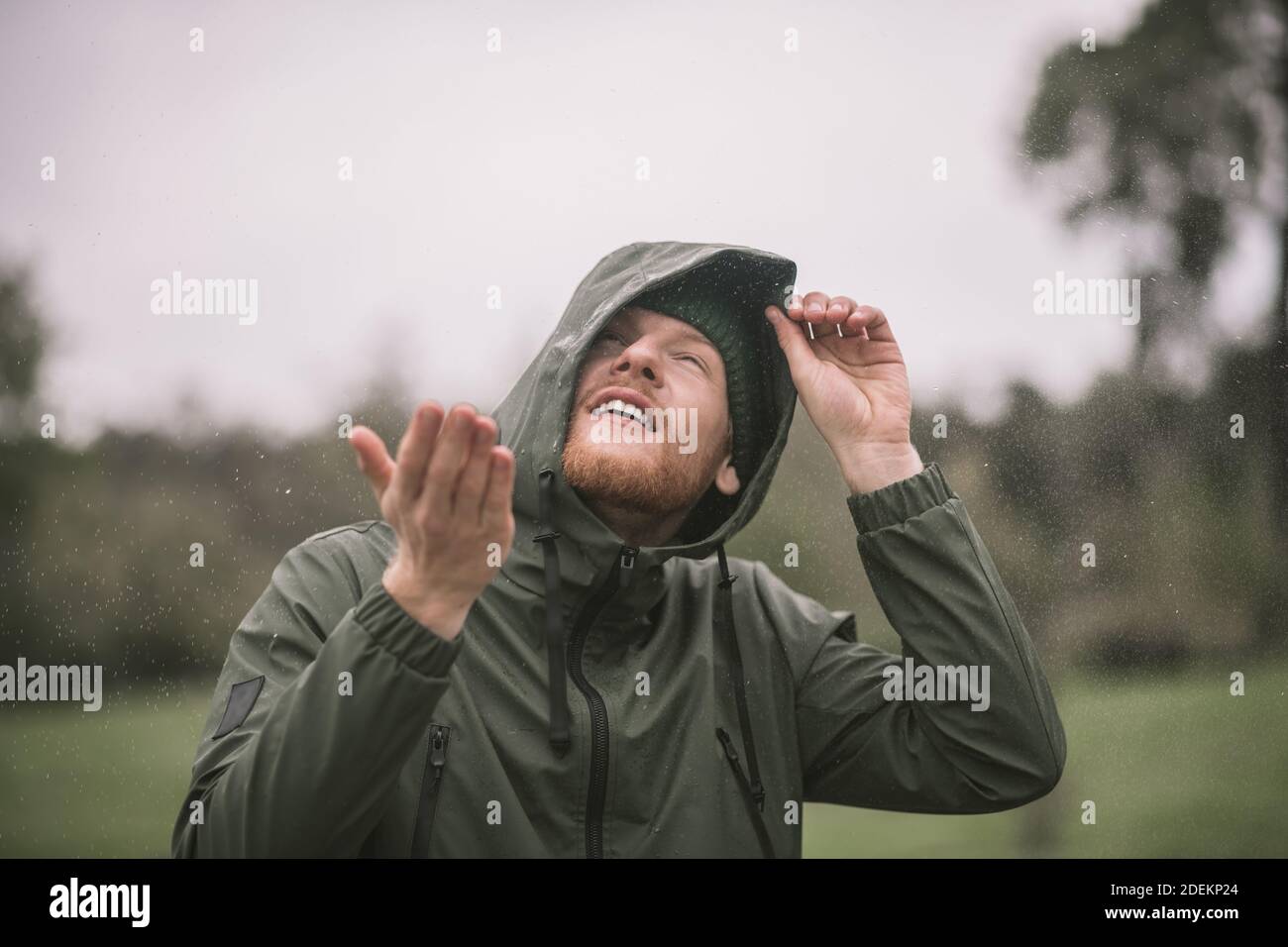 Young man in a green coat catching rain drops Stock Photo - Alamy
