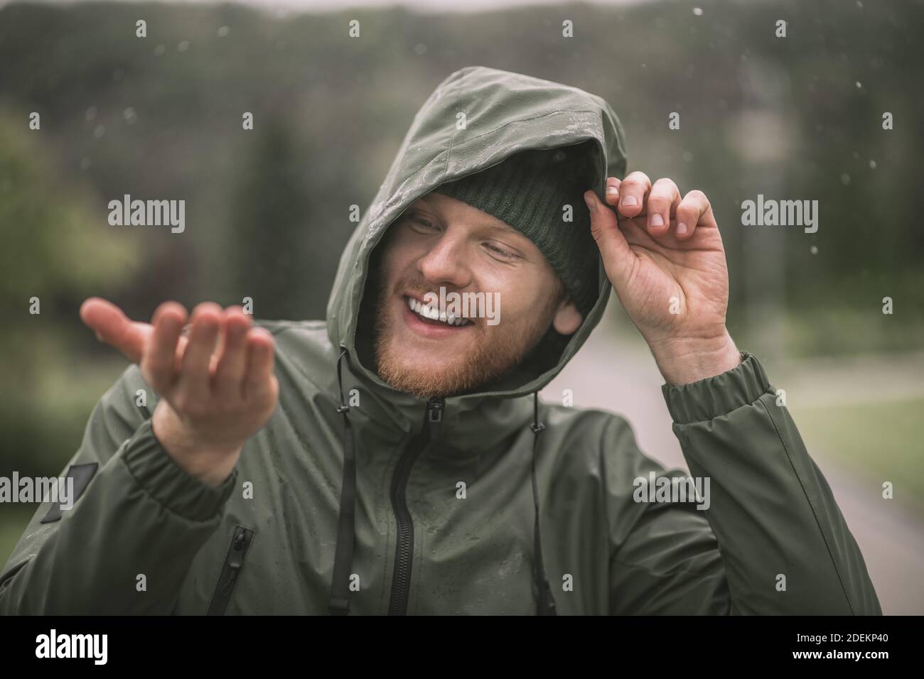 Man in a green coat catching rain drops and smiling Stock Photo - Alamy