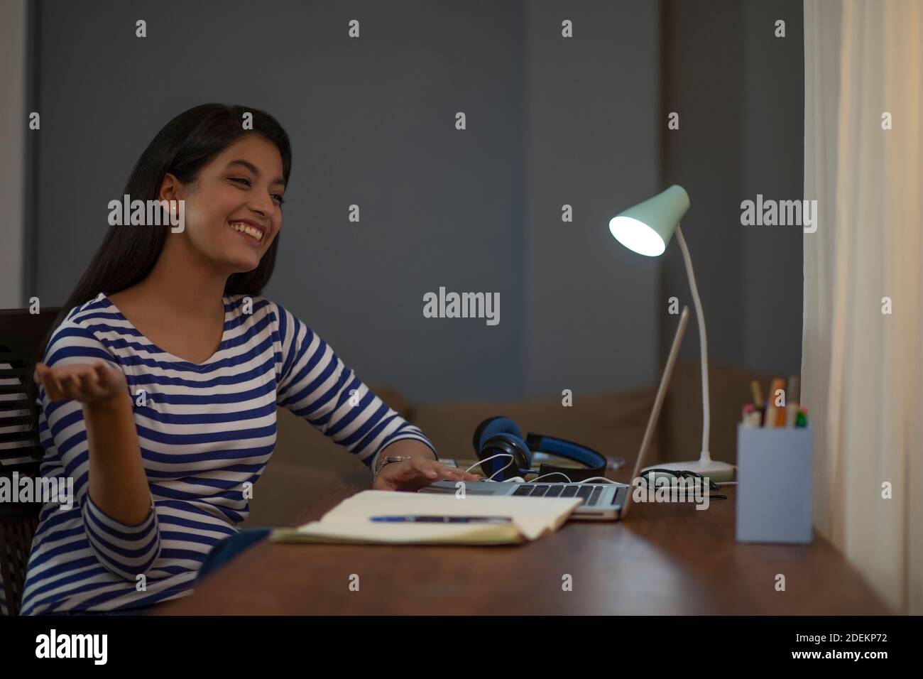 Girl talking on a video call late at night while completing her ...
