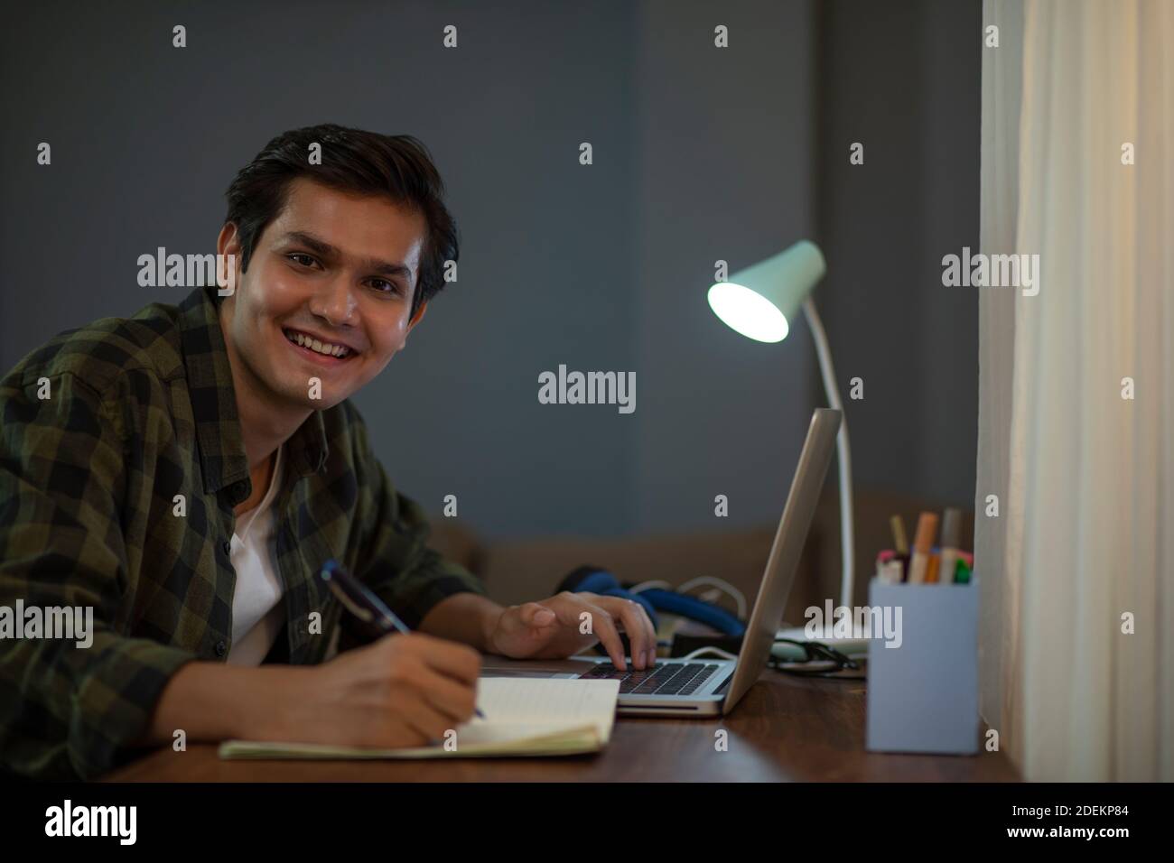 Boy smiling while writing his assignment during online class Stock ...
