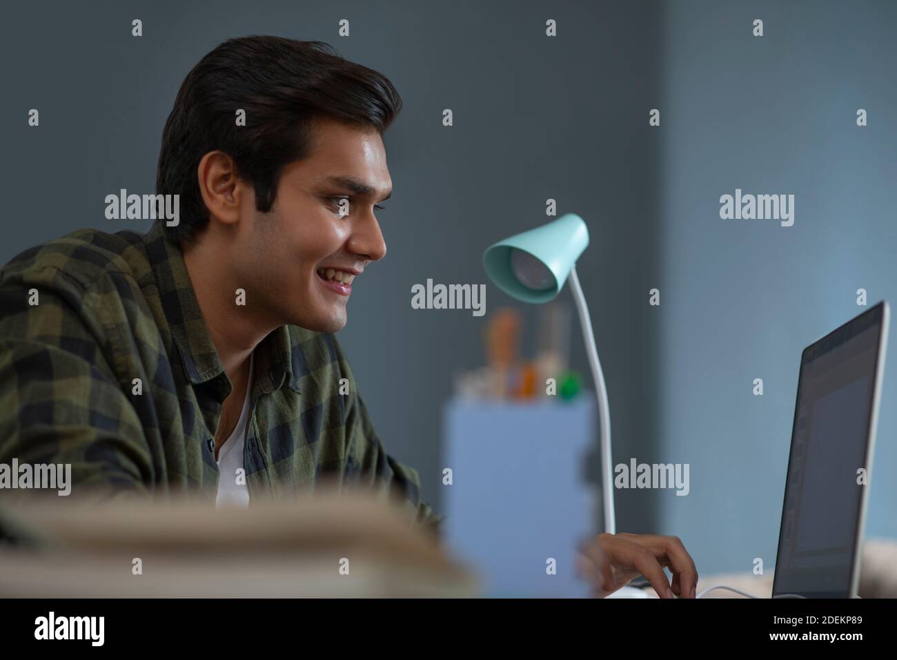 A YOUNG COLLEGE STUDENT ATTENDING ONLINE CLASS ON LAPTOP Stock Photo ...