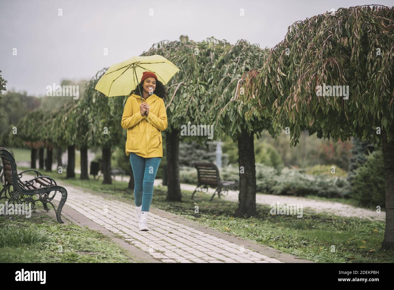 Cute mulatta with yellow umbrella looking happy Stock Photo - Alamy