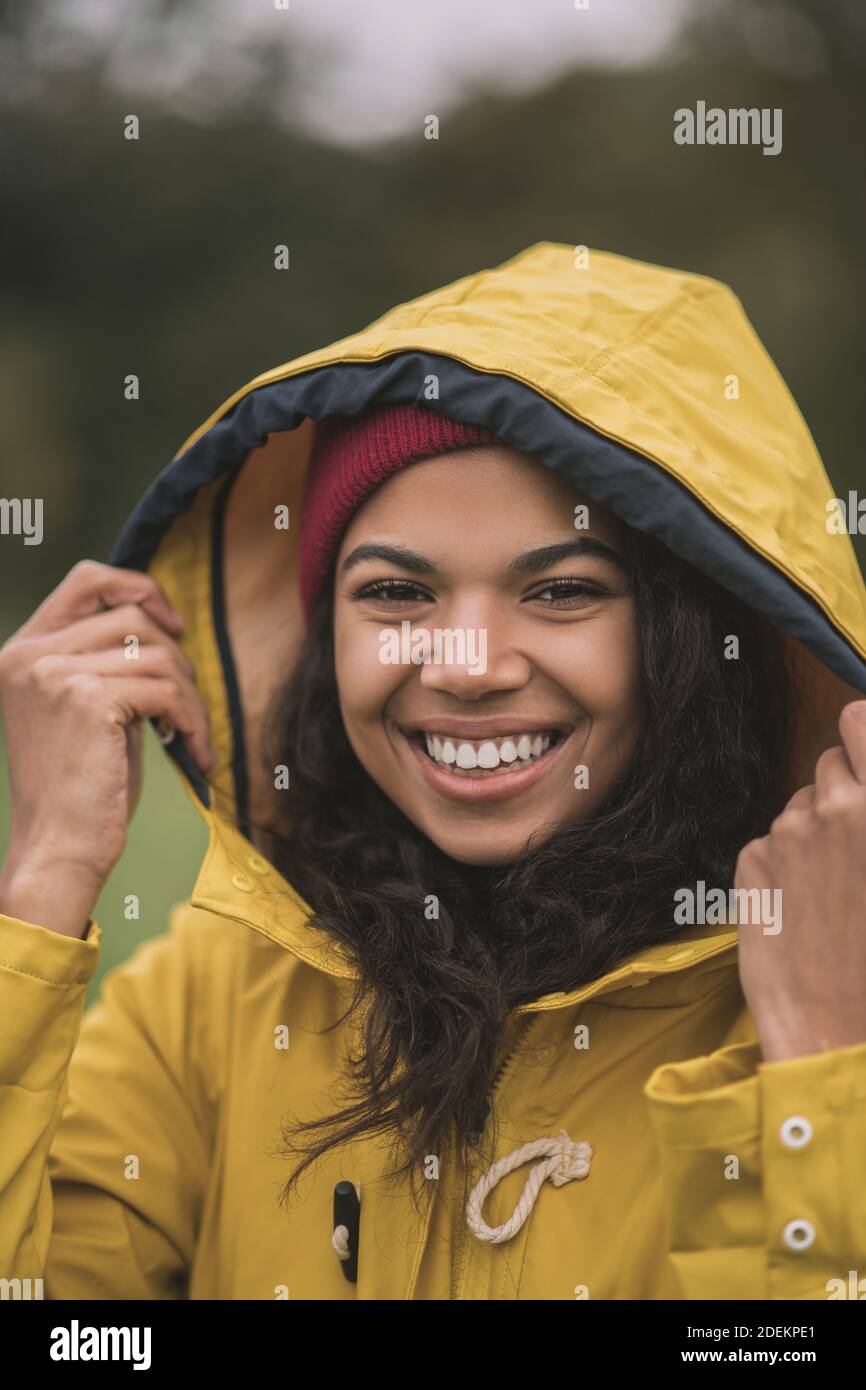 Pretty mulatta in yellow coat smiling nicely Stock Photo - Alamy