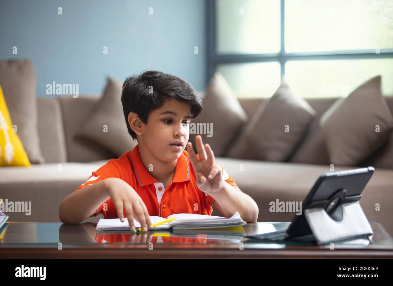 YOUNG BOY ANSWERING TO HIS TEACHER DURING HIS ONLINE CLASS Stock Photo ...