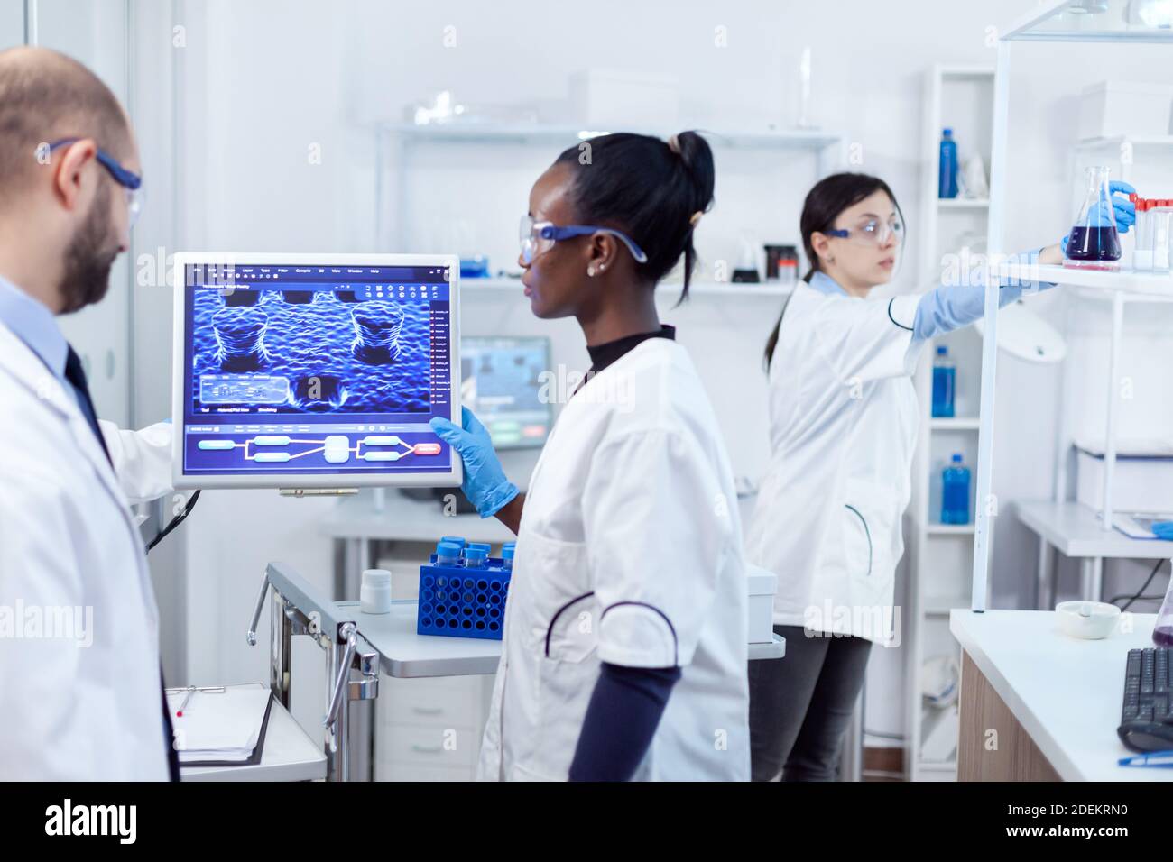 Multiethnic team of medical researchers working together in sterile lab ...