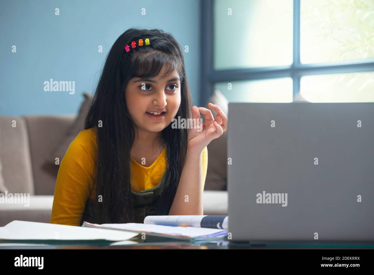 Young girl calculating numbers on her fingertips in front of her laptop ...
