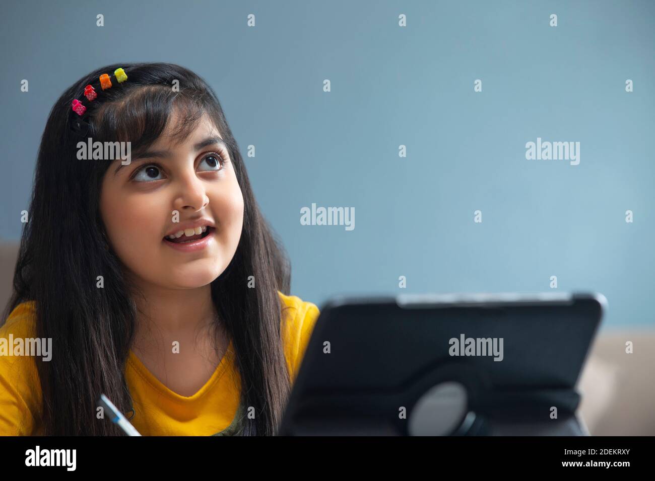 Young girl thinking of an answer with an innocent smile on her face ...