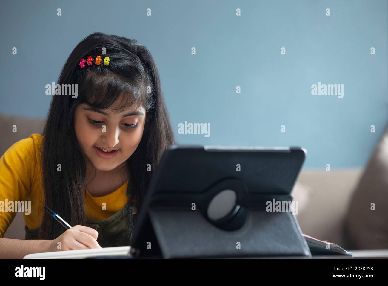 Young girl writing notes in her notebook while sitting in front of her ...