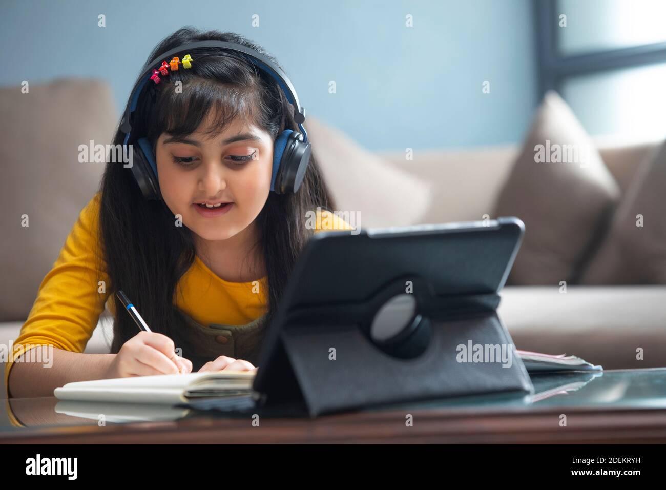 Young girl writing in her notebook while listening her lecture with her ...